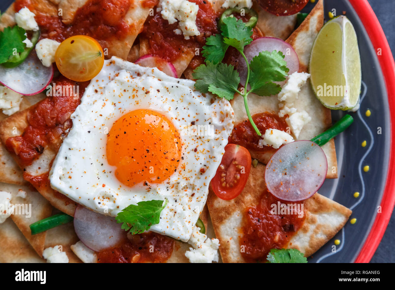 Mexican breakfast: chilaquiles with egg, avocado and vegetables close ...