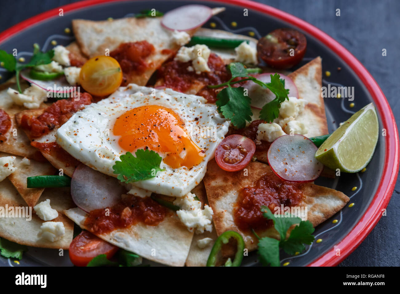 Mexican breakfast: chilaquiles with egg, avocado and vegetables close ...