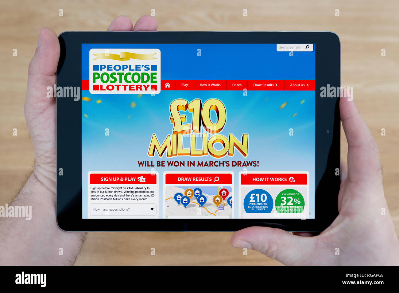 A man looks at the People’s Postcode Lottery website on his iPad tablet ...
