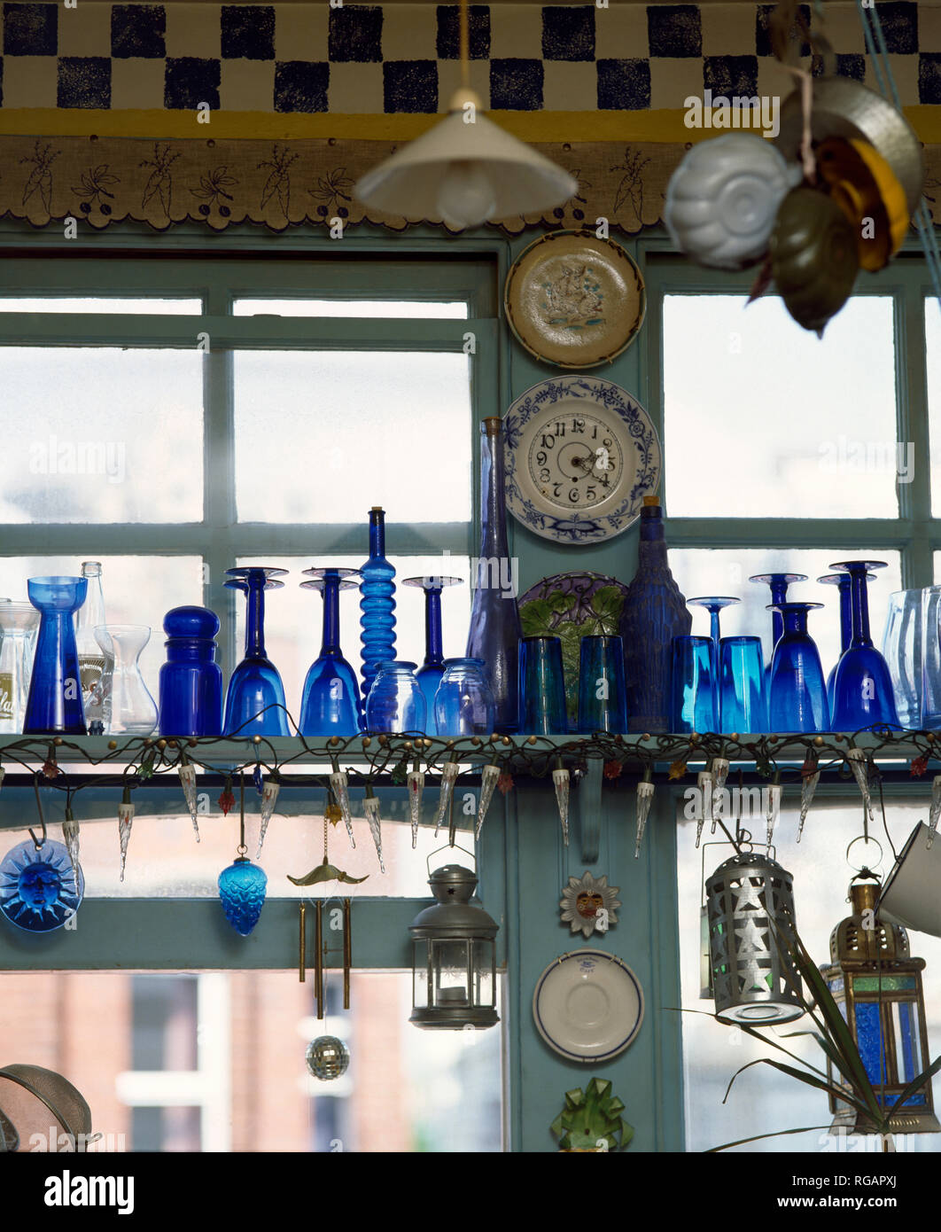 Collection of blue glassware on shelf across window Stock Photo - Alamy