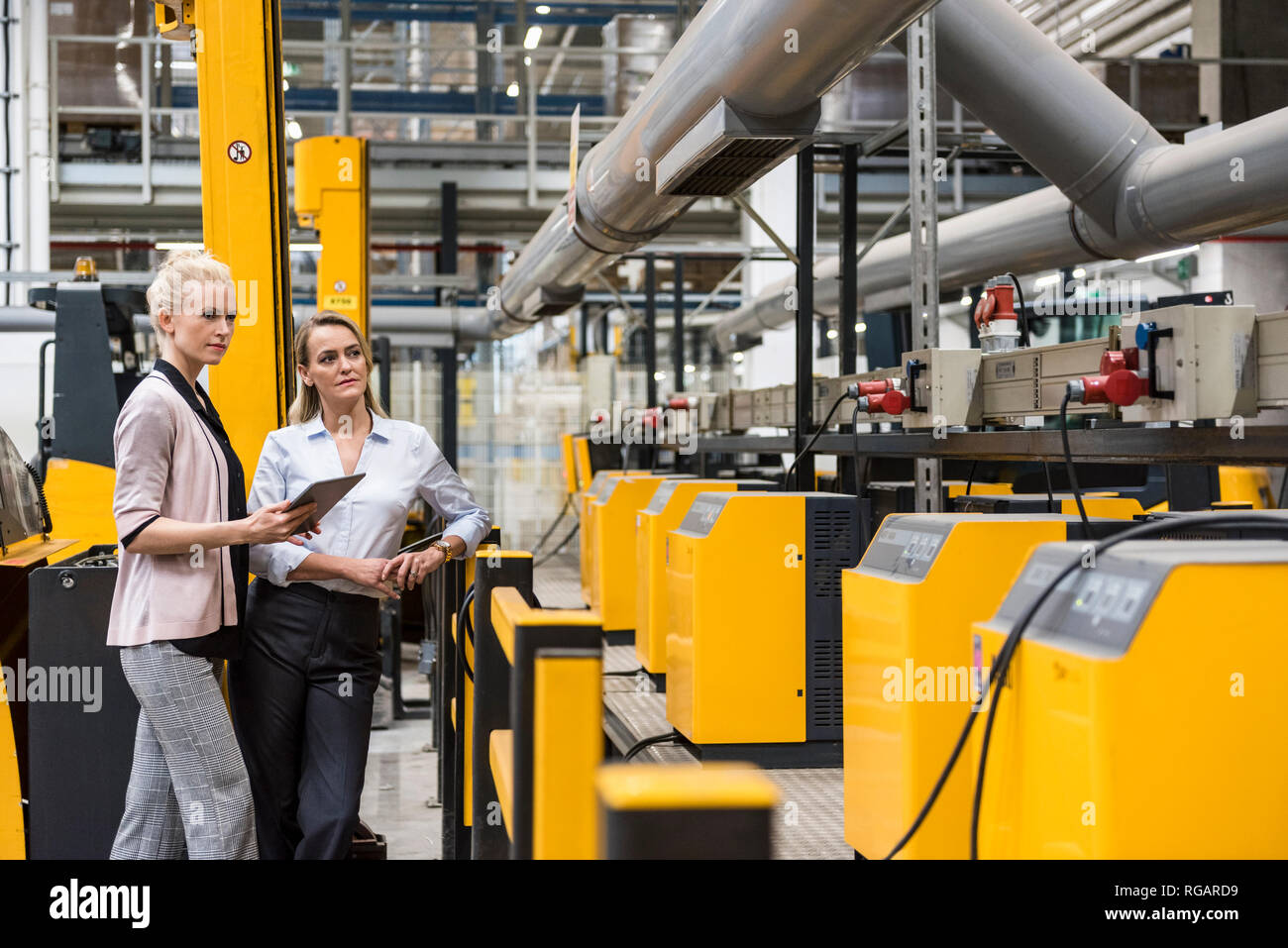 Two women with tablet looking at machine in factory shop floor Stock ...