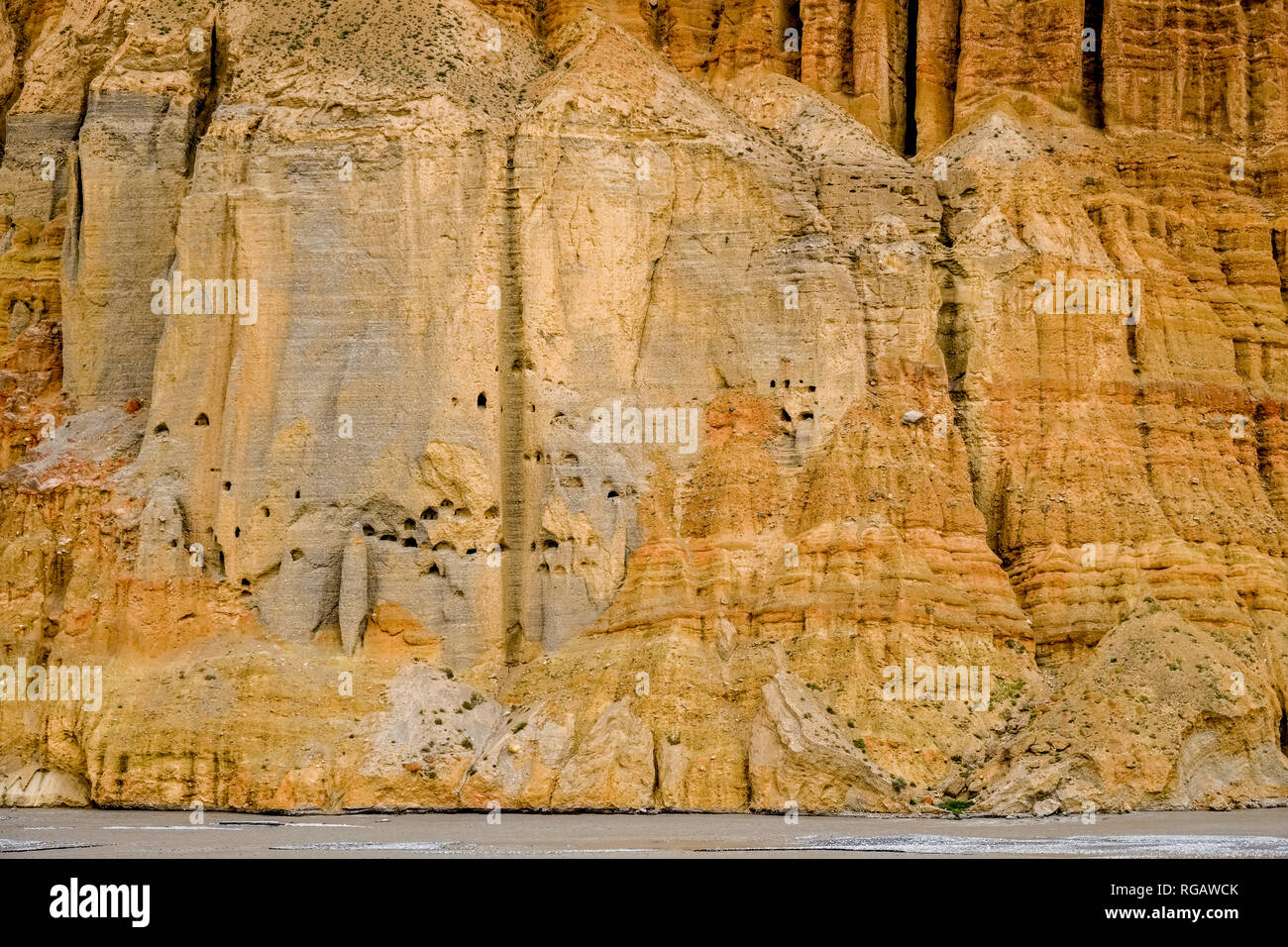 Steep colorful rock cliffs with man made caves, seen across the Kali ...