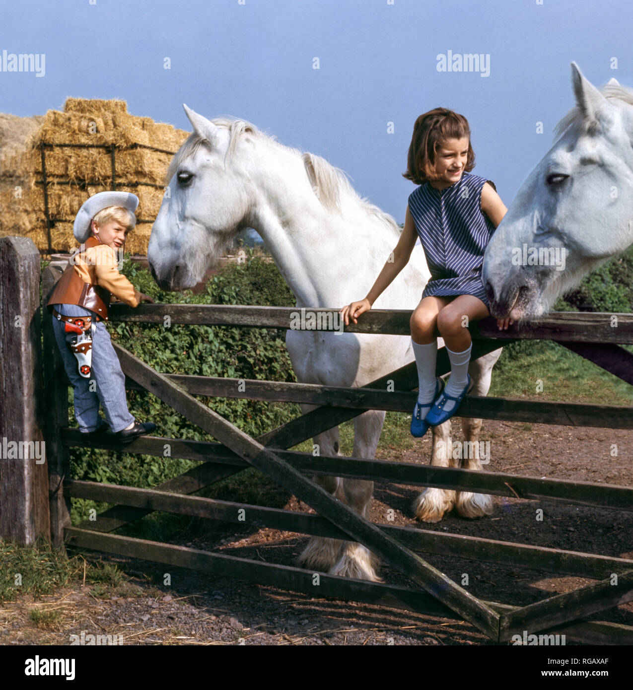 Small boy dressed as a cowboy and his sister with two very large Shire ...