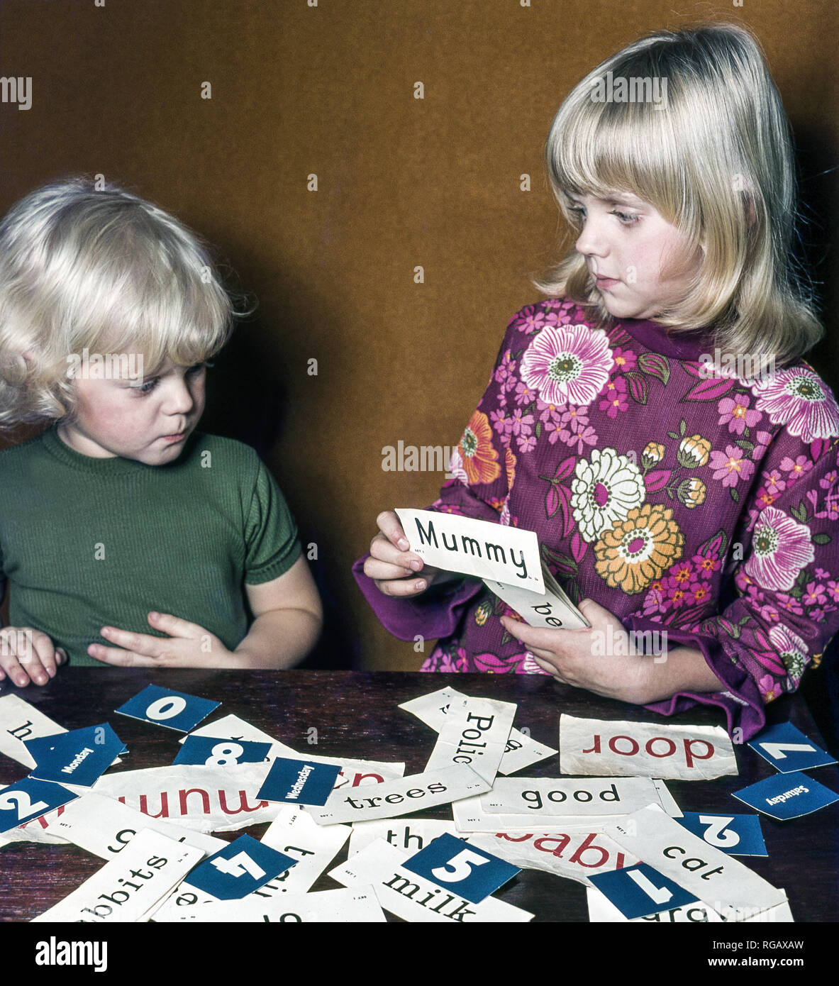 An older girl teaching her younger brother to read with the use of ...