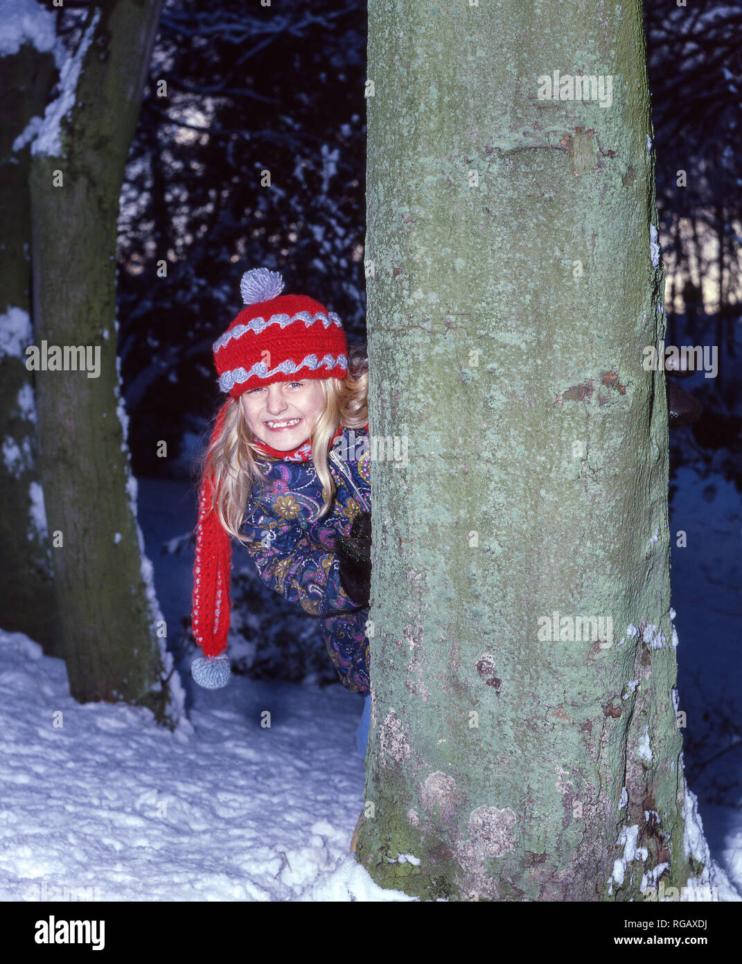Young girl playing hide and seek in the snow Stock Photo - Alamy