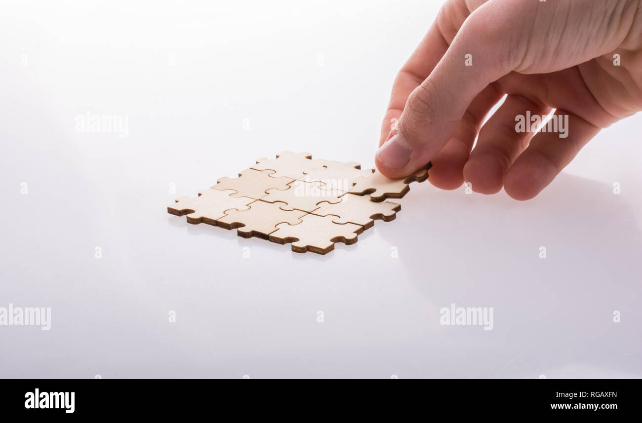 Hand completing a puzzle group on a white background Stock Photo - Alamy