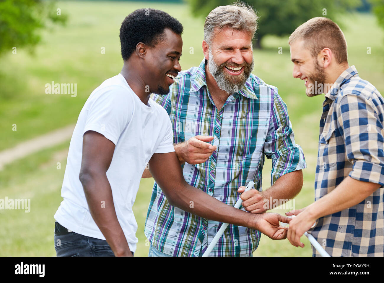 Three men as friends laugh at difficulties in building a tent Stock ...