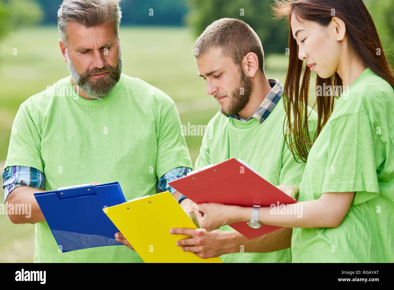 Three people volunteers with clipboard plan together a environmental ...