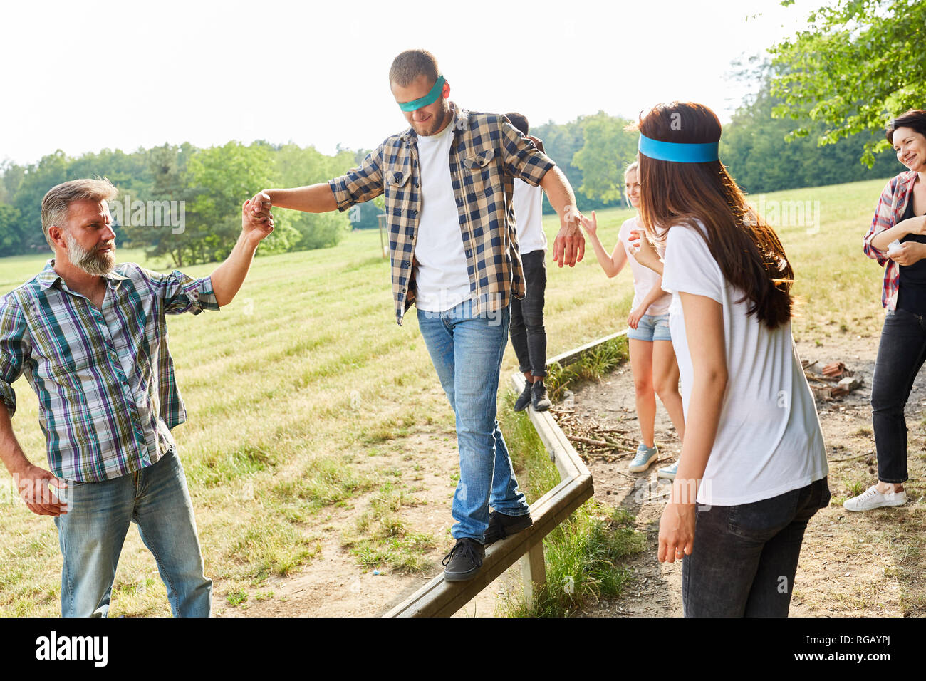 Group of young people while balancing together on a teambuilding event ...