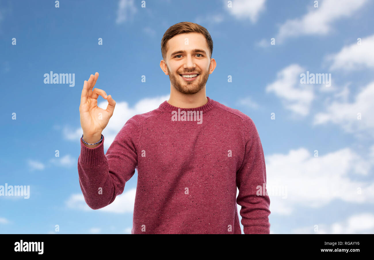 smiling man showing ok hand sign over blue sky Stock Photo - Alamy