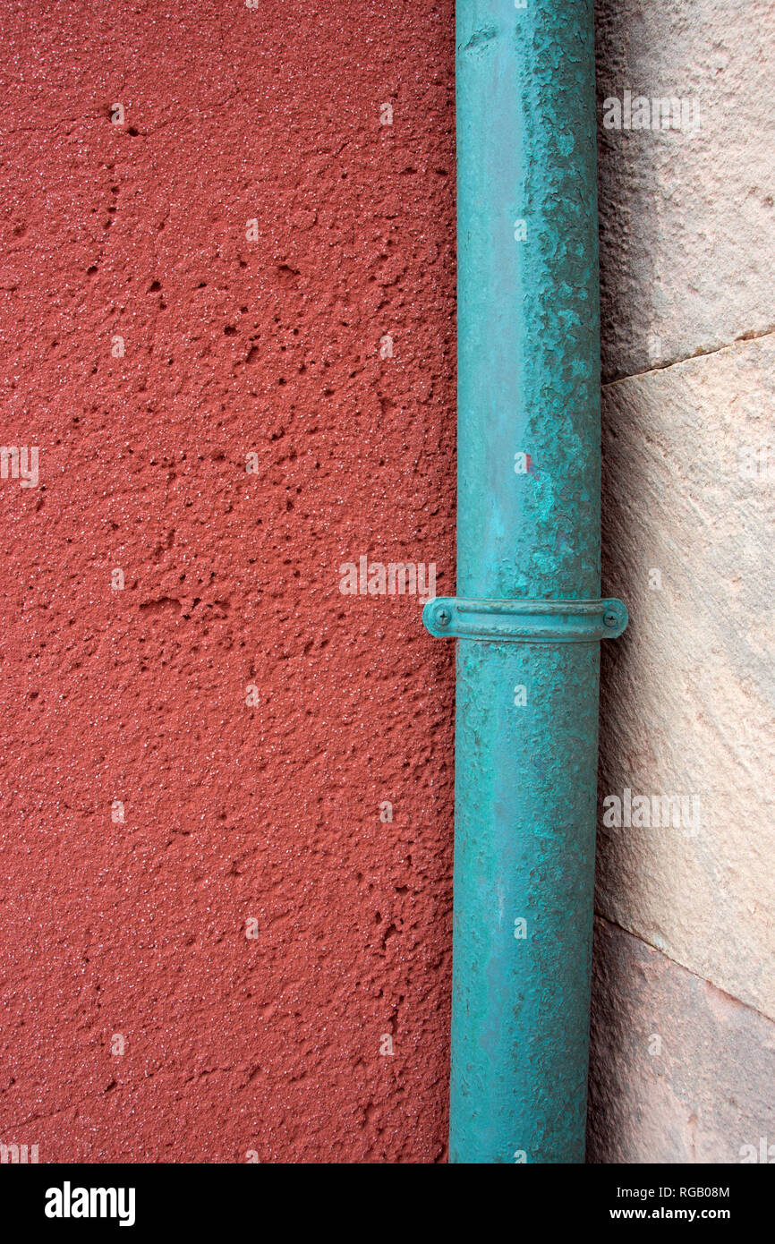 green painted down pipe in the corner of a pink and white wall join ...