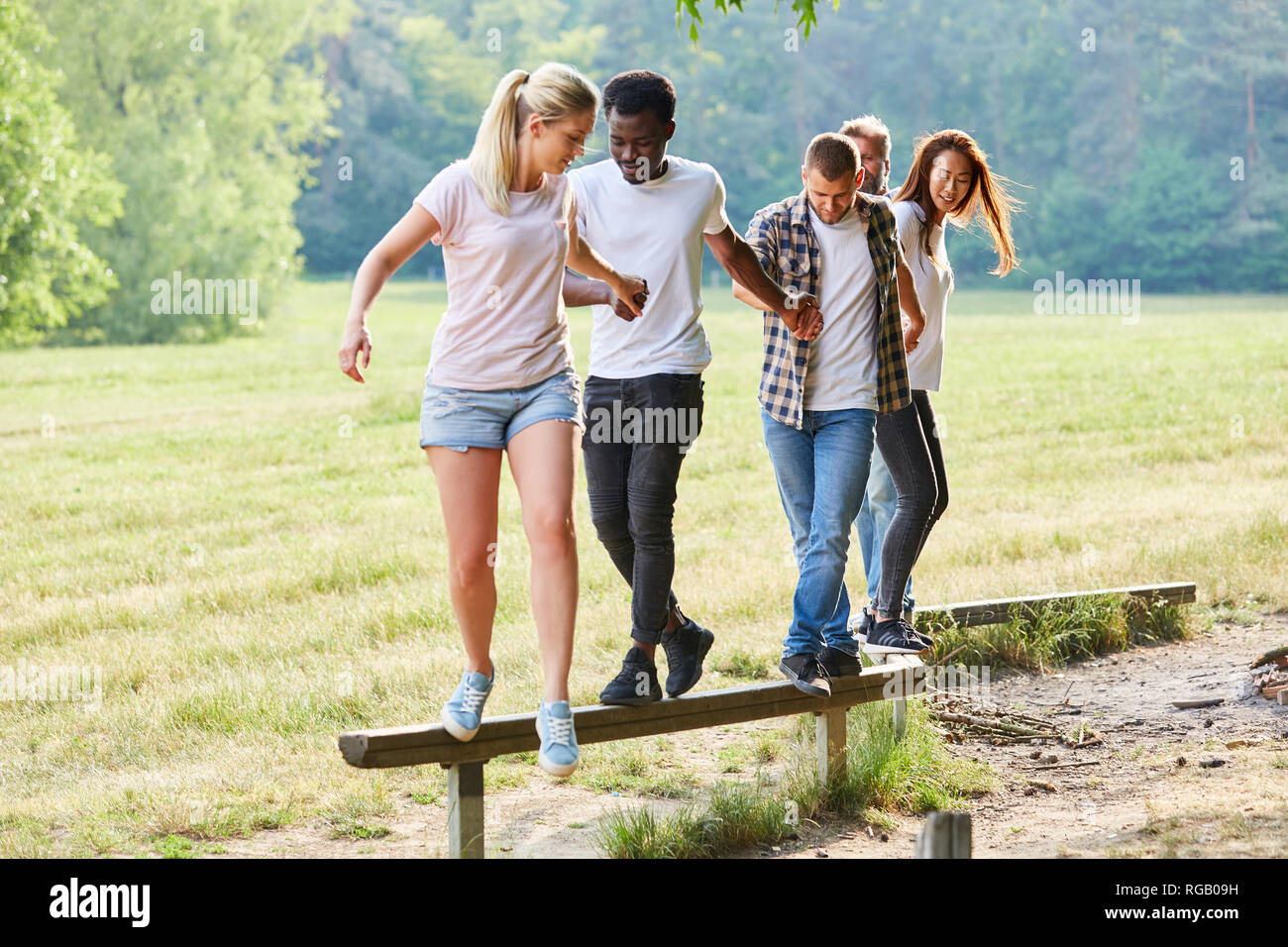 Group of friends balancing on a beam on a trim path Stock Photo - Alamy