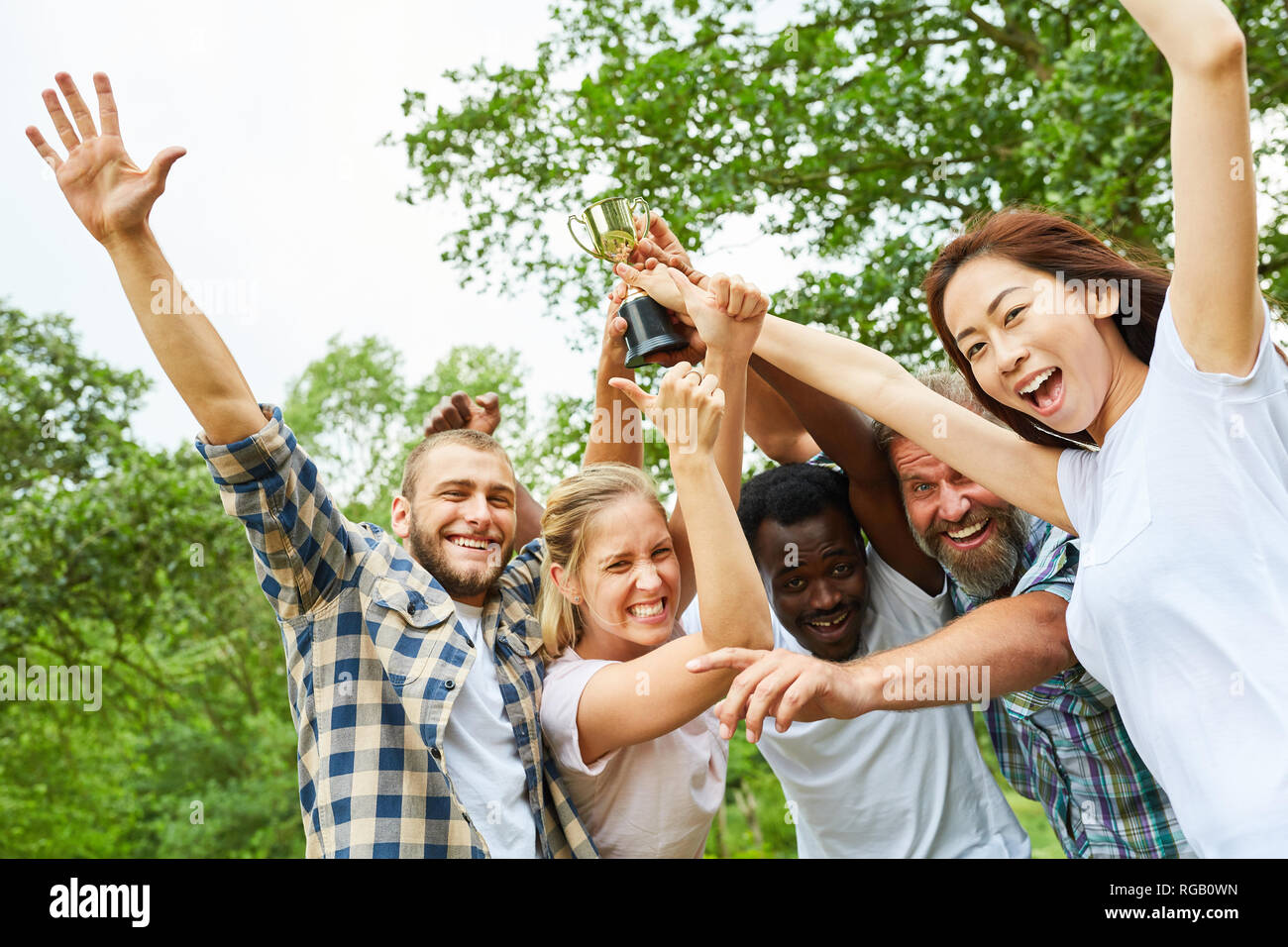 Young people with trophy as a successful team cheer for victory after a ...