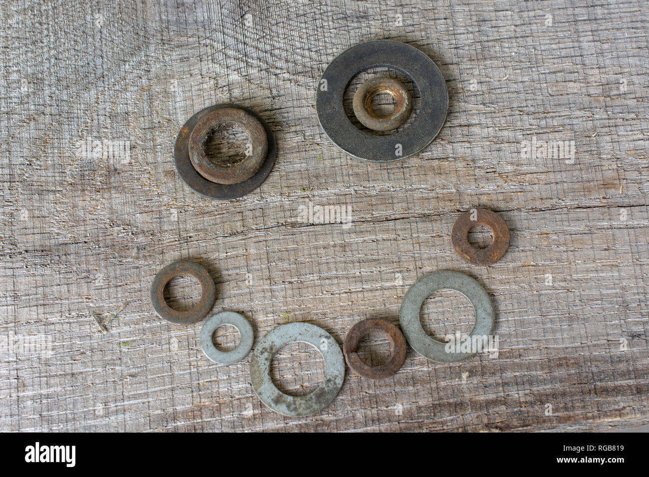 A happy face arranged from rusty metal washers placed on a rough piece ...