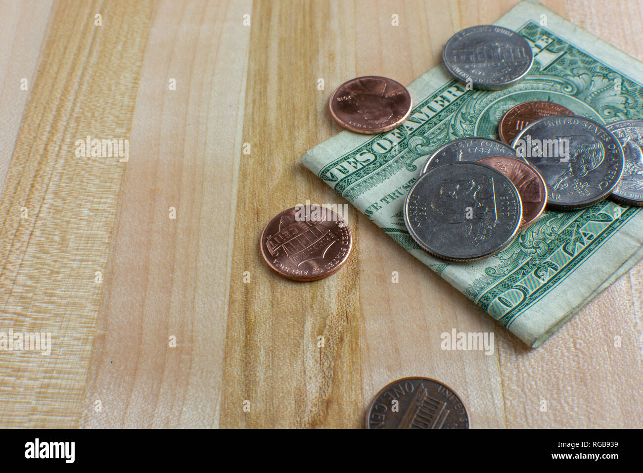 Pocket change and a folded dollar bill placed onto a wooden table. USA ...