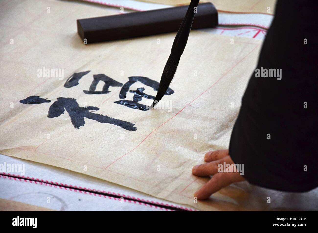 A hand holding a paintbrush and writing a chinese character fu ...