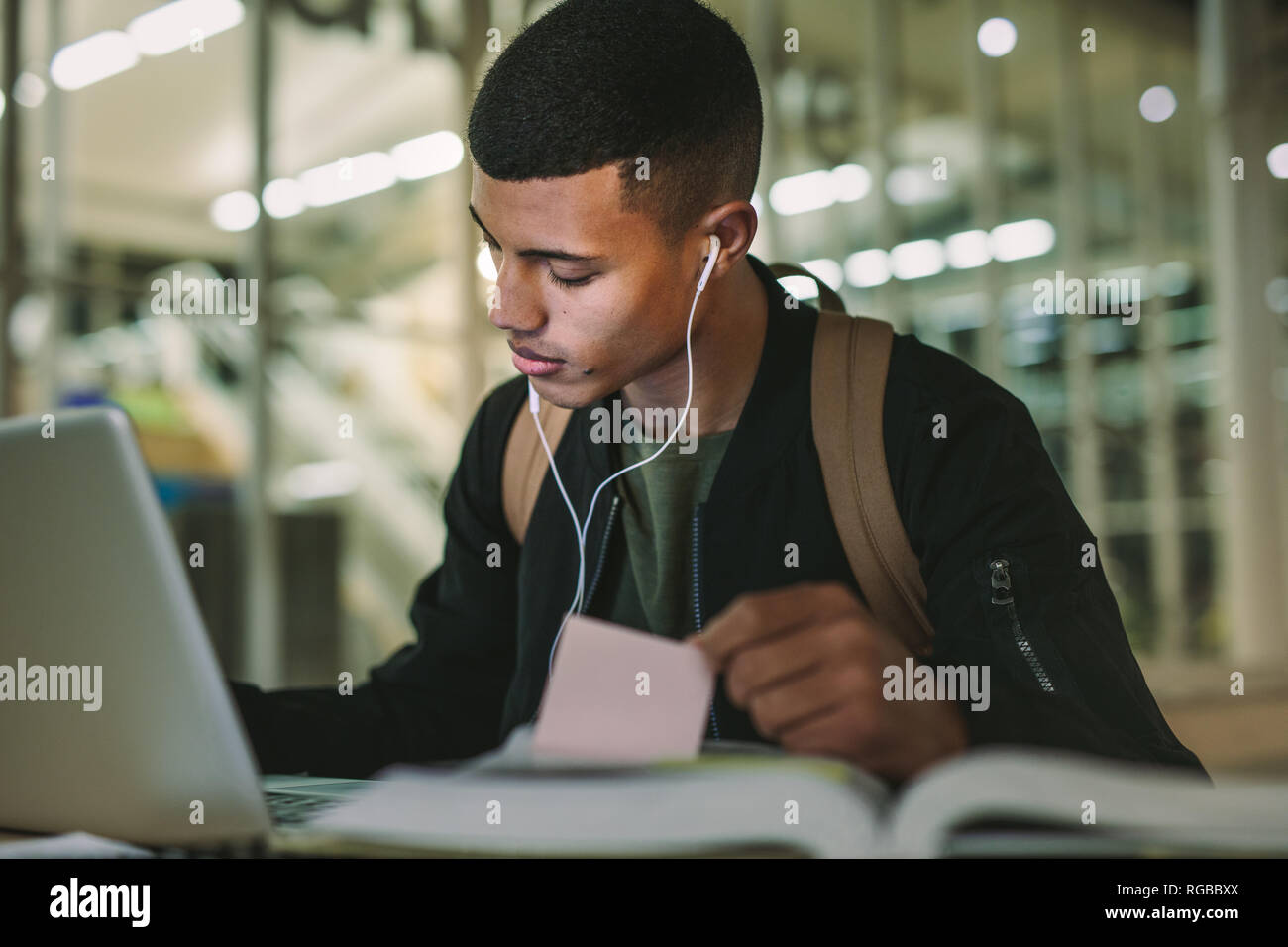 Male student sitting making notes with laptop on table preparing class ...