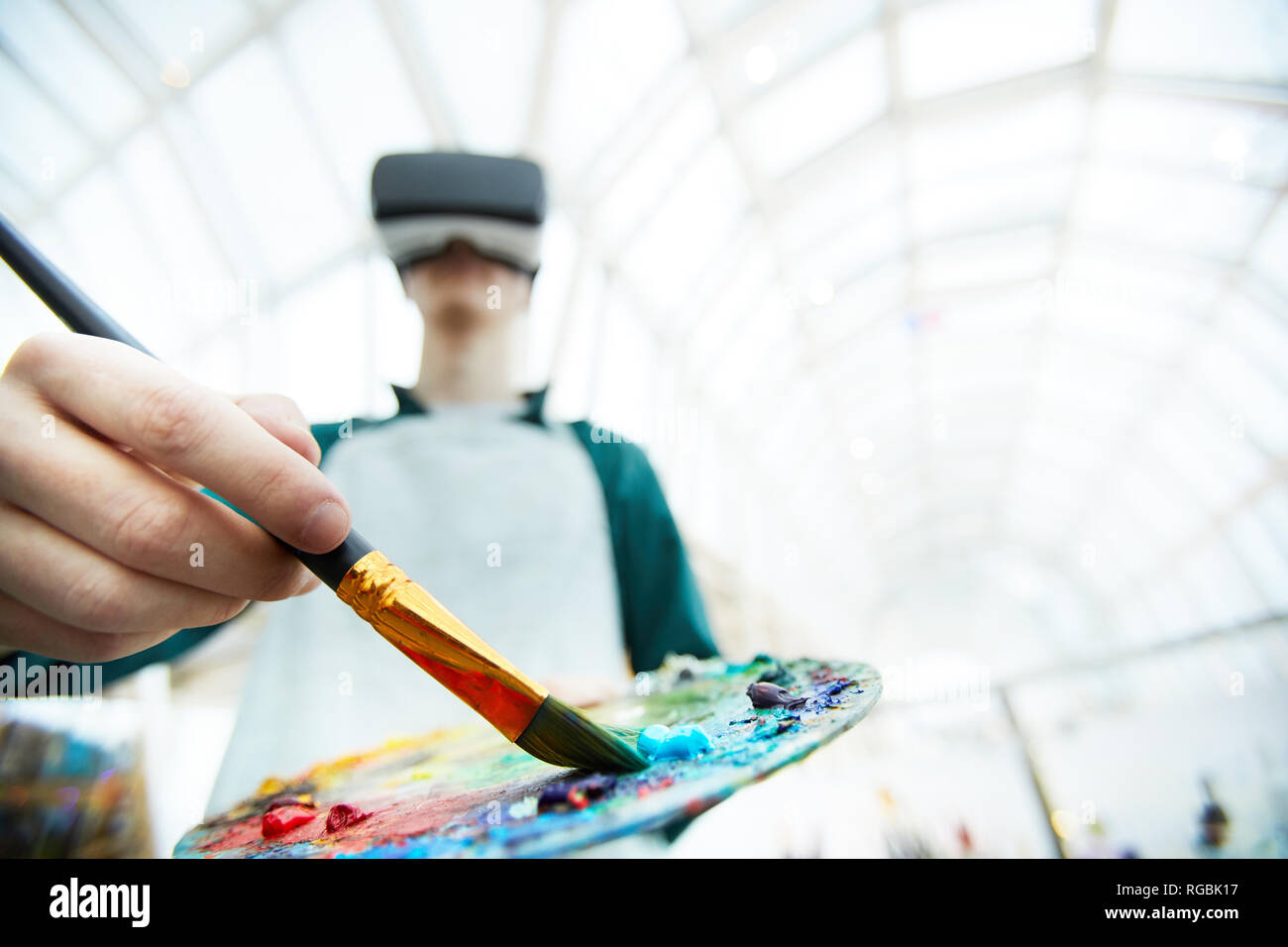 Low angle portrait of young man wearing VR headset painting picture and ...