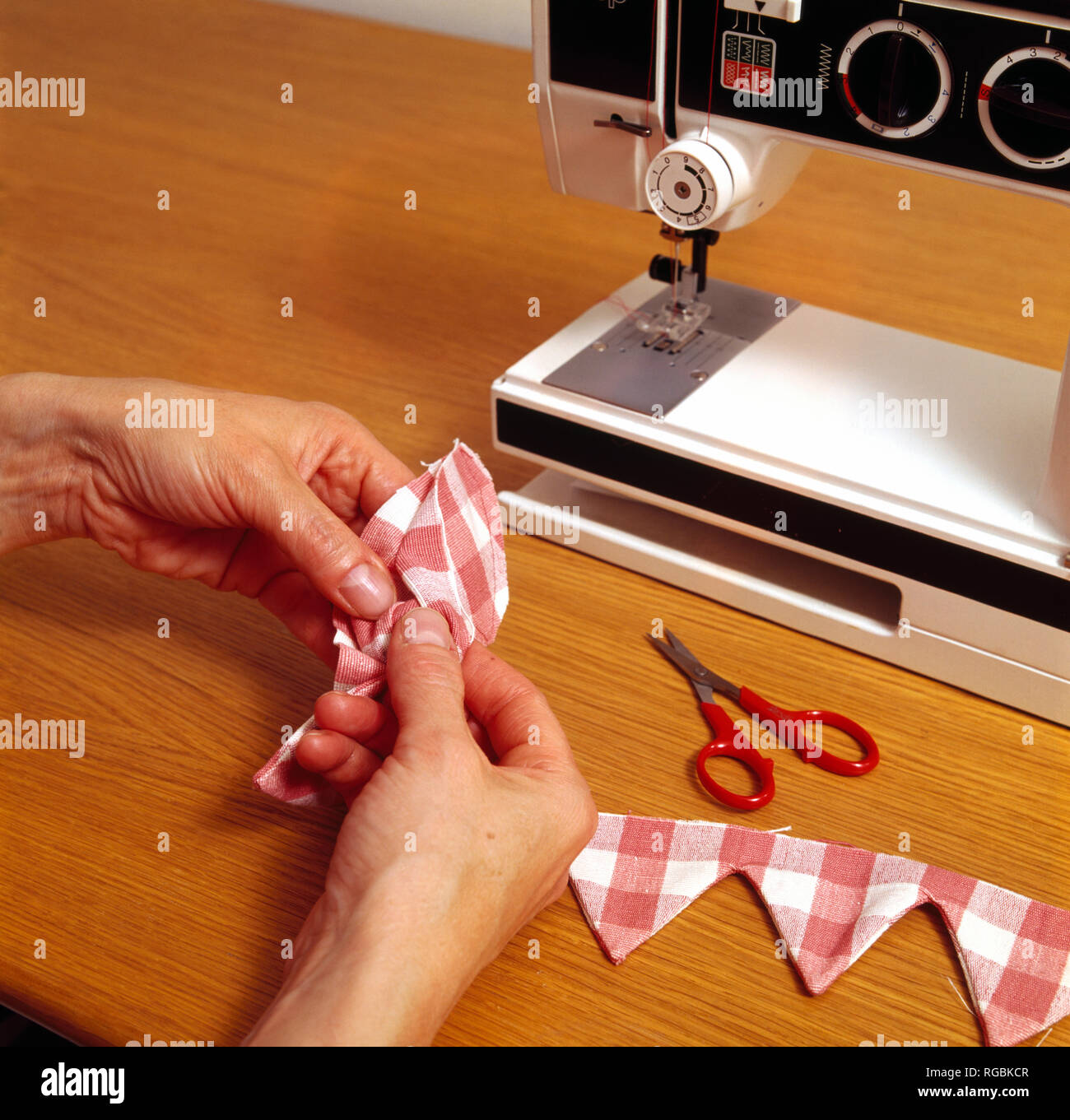 Using a sewing machine to make a red checked edging Stock Photo - Alamy