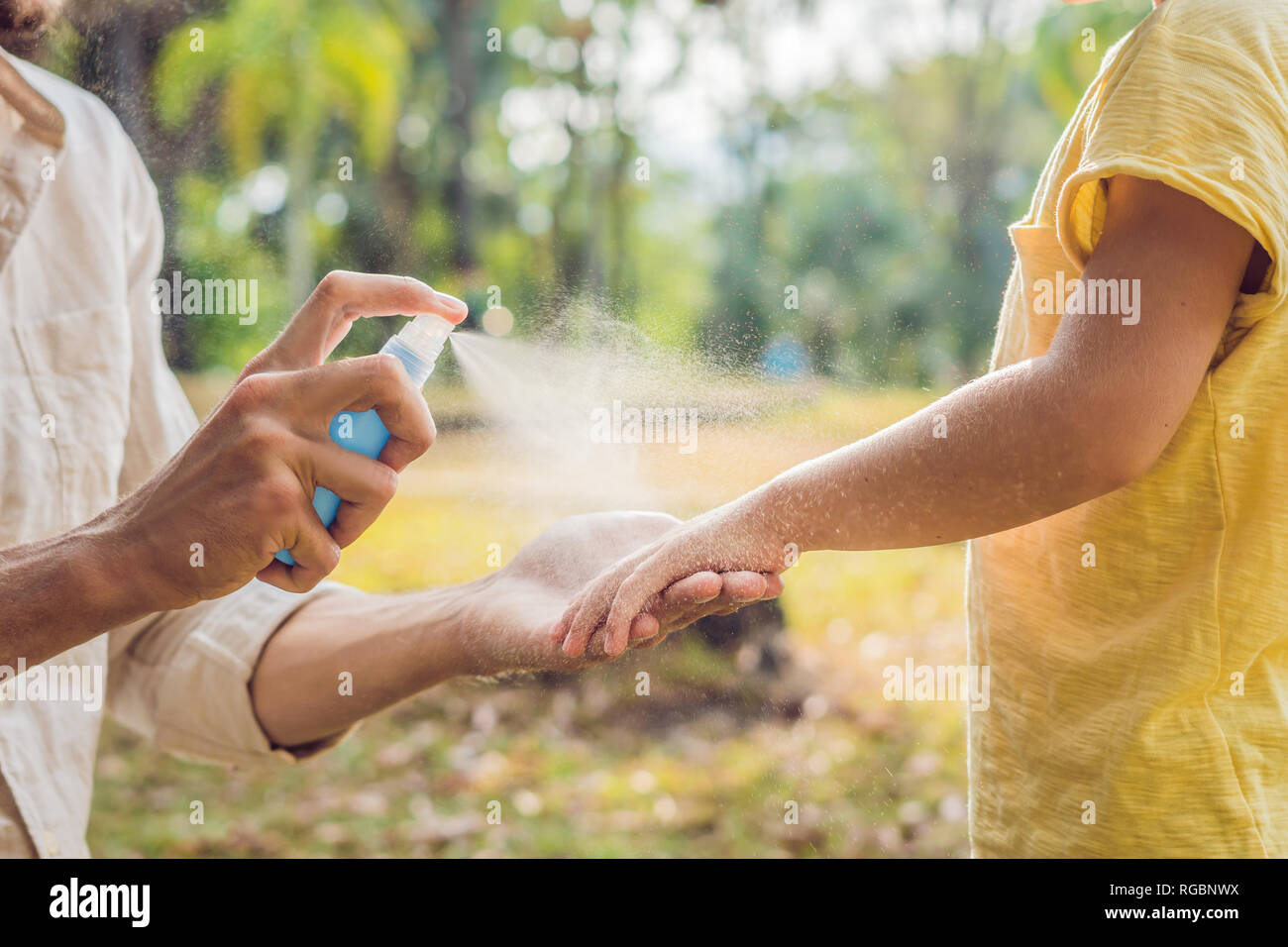 dad and son use mosquito spray.Spraying insect repellent on skin ...