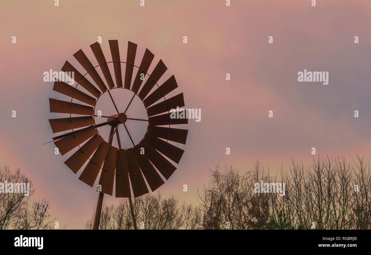 Old vintage rusty windmill at sunset, colorful sky and clouds ...