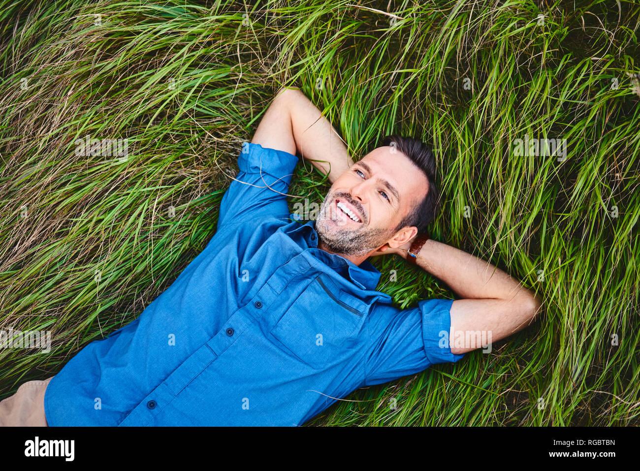 Relaxed happy man lying in grass Stock Photo - Alamy