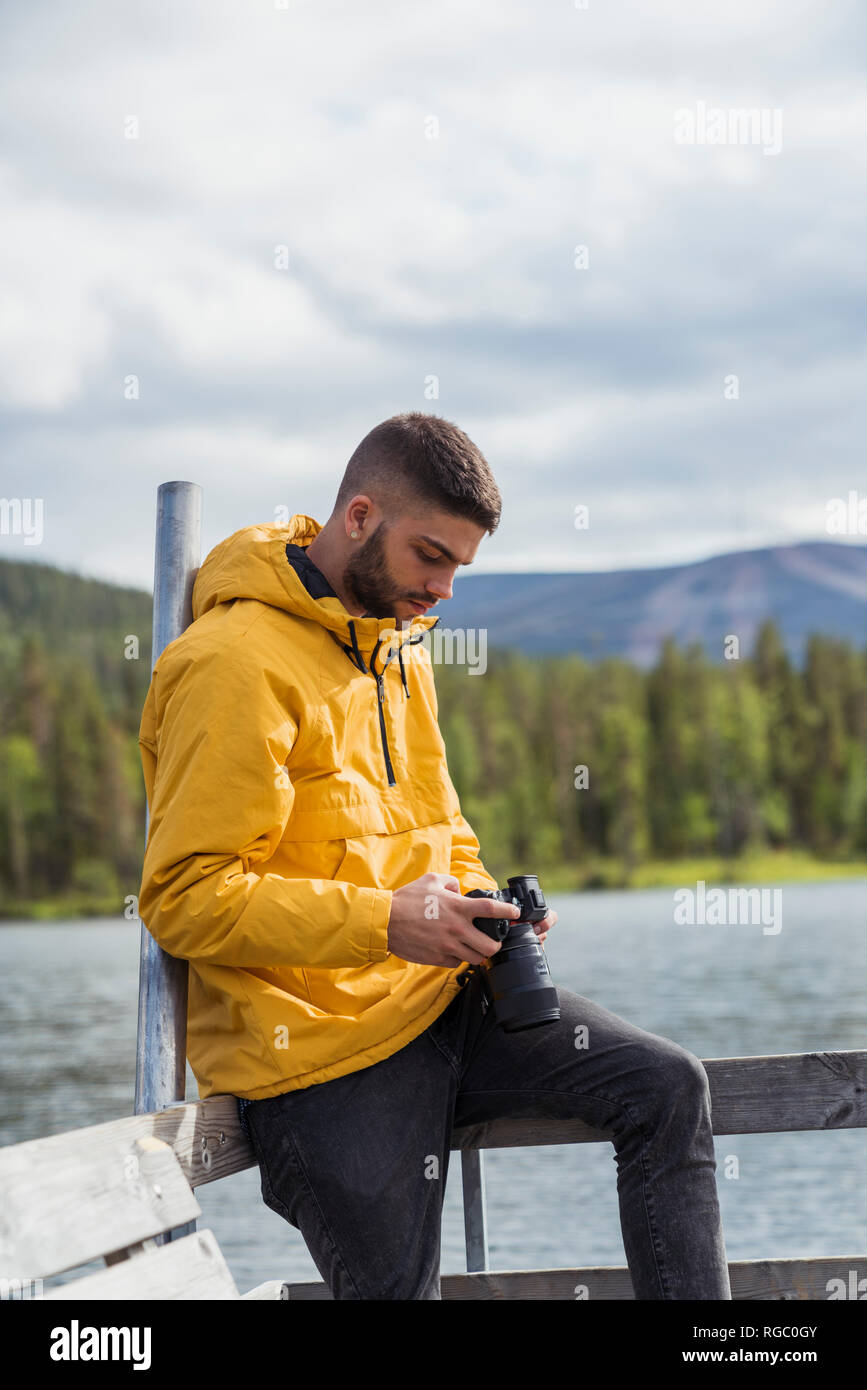 Finland, Lapland, young man with a camera on jetty at a lake Stock ...