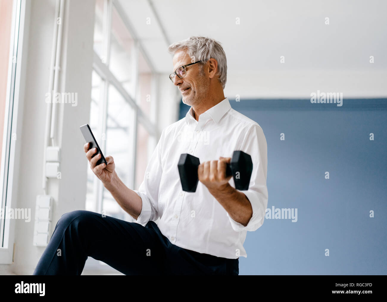 Successful manager using smartphone and training with a dumbbell Stock ...
