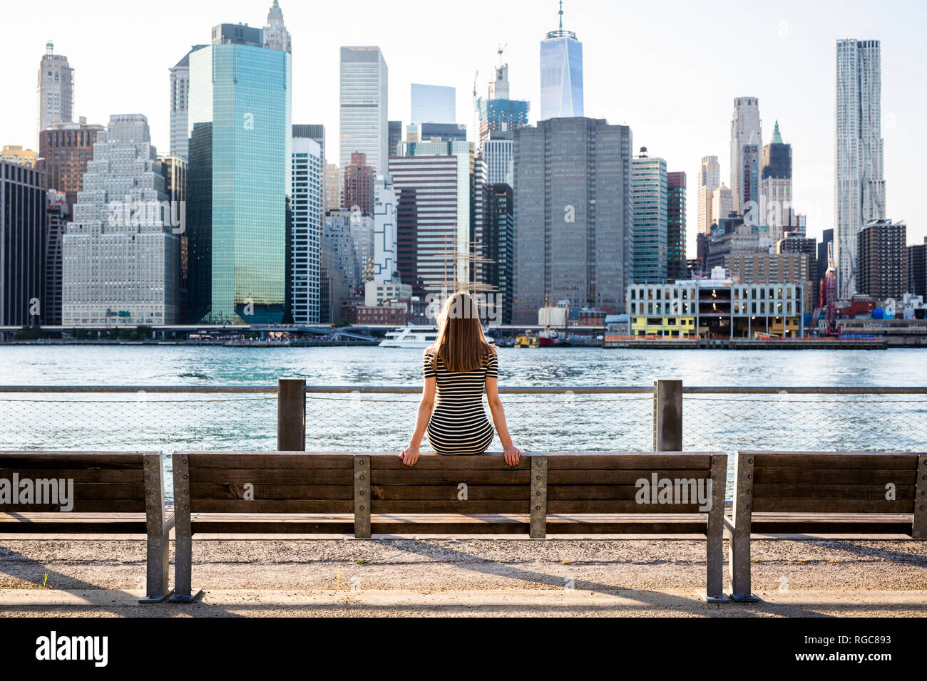 USA, New York, Brooklyn, back view of woman sitting on bench in front ...