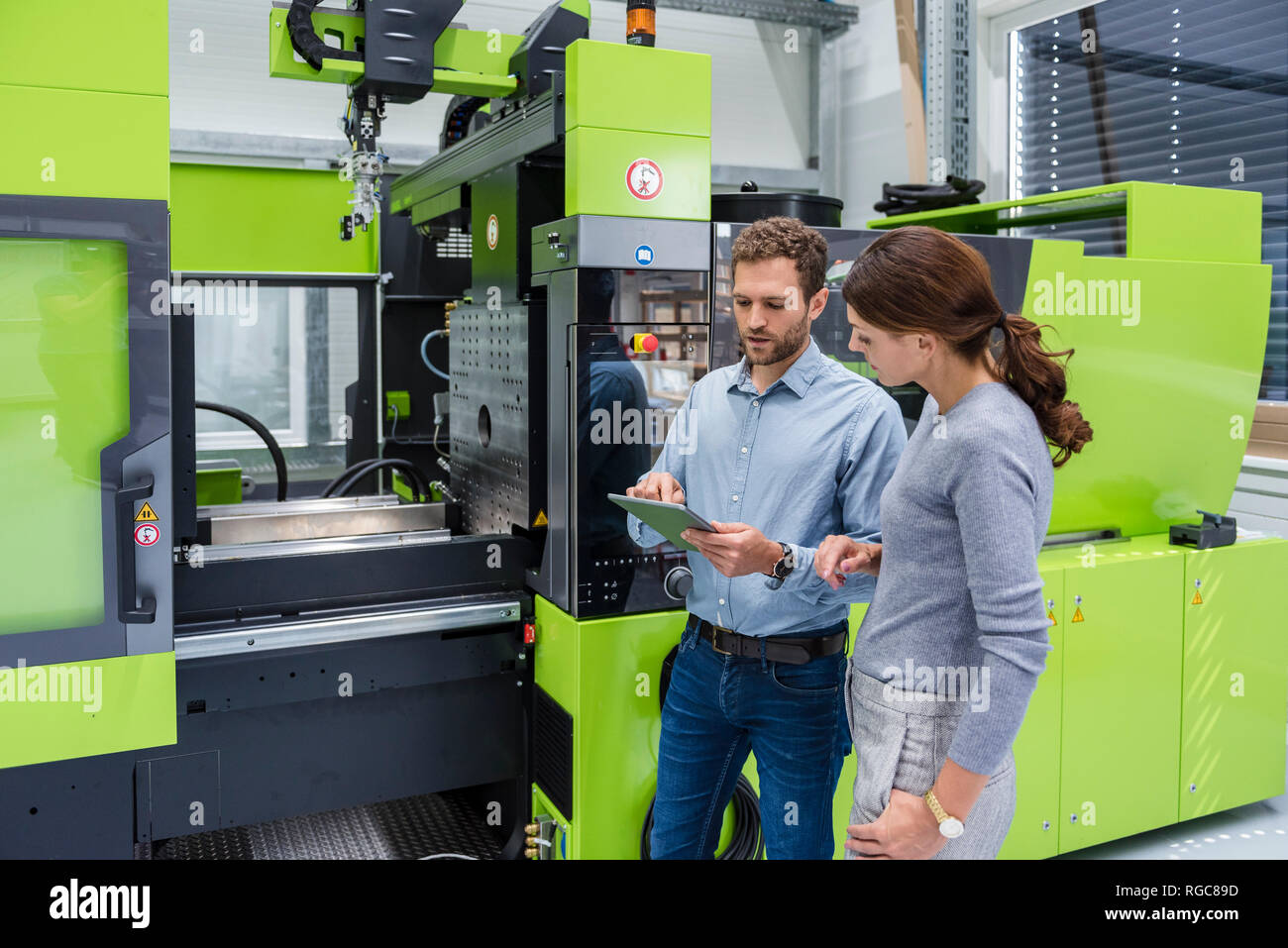 Colleagues in high tech company controlling manufacturing machines ...