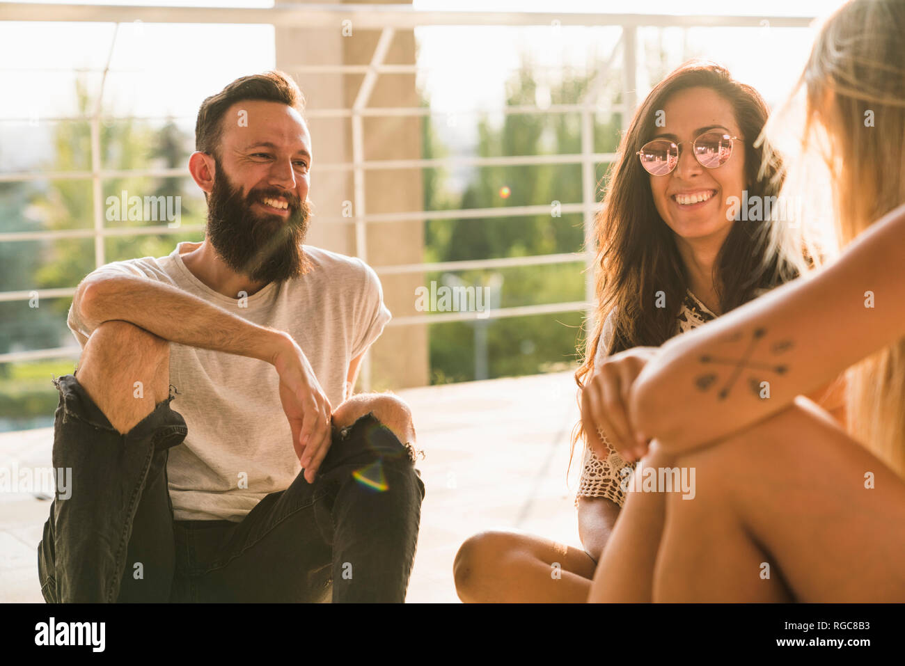 Happy friends sitting down relaxing in the city Stock Photo - Alamy