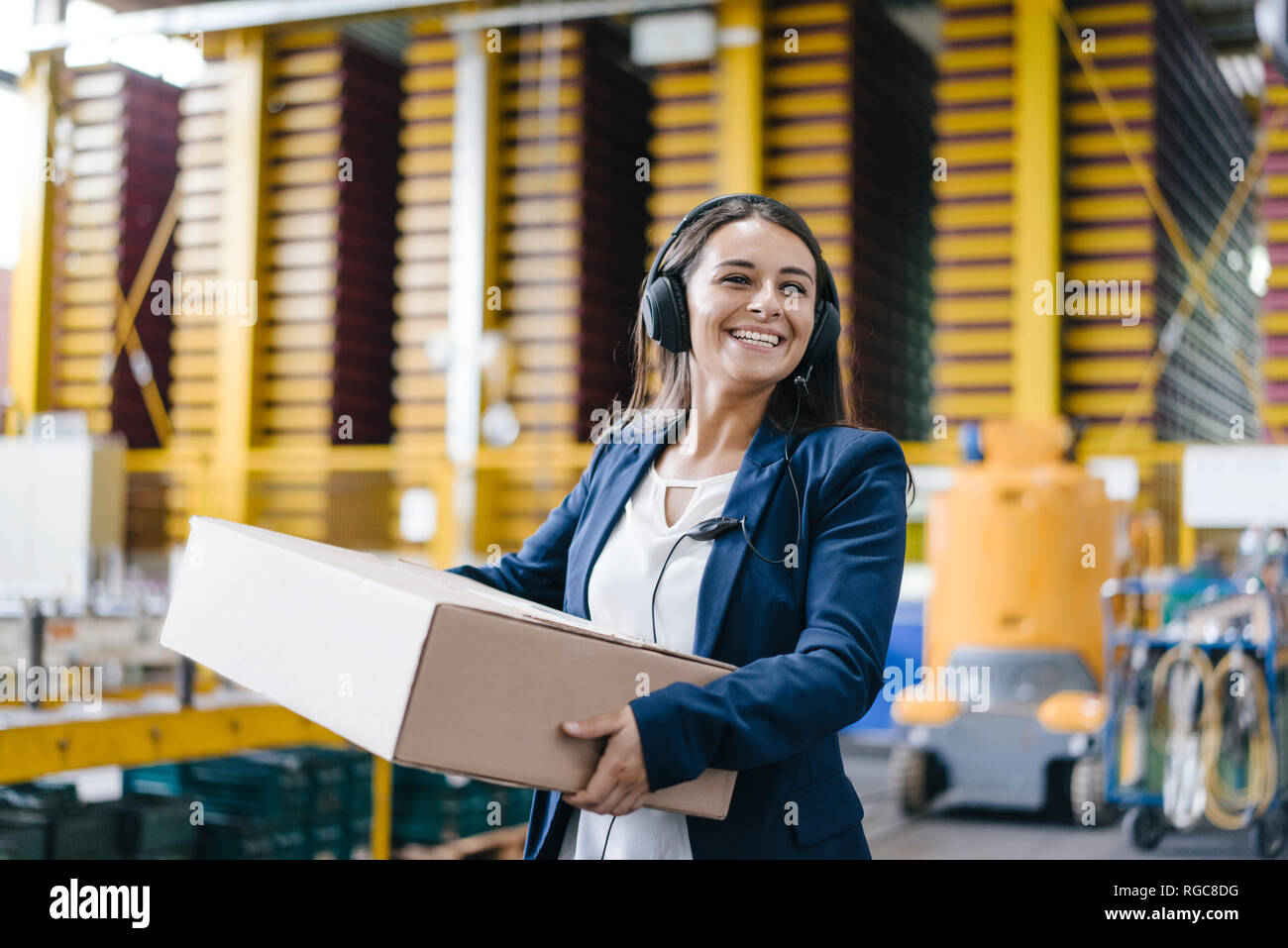 Young woman working at parcel service, carrying parcel in warehouse ...