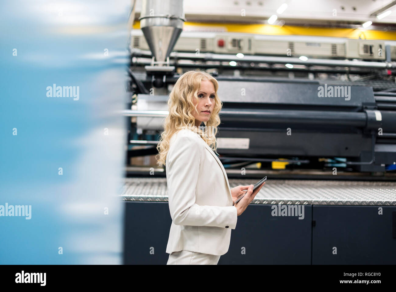 Woman with tablet at machine in factory shop floor looking around Stock ...