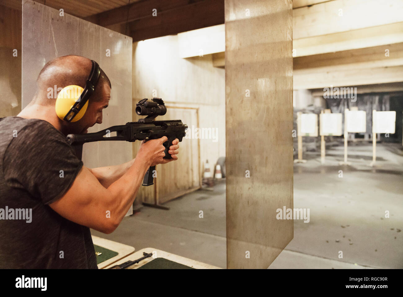 Man aiming with a rifle in an indoor shooting range Stock Photo - Alamy