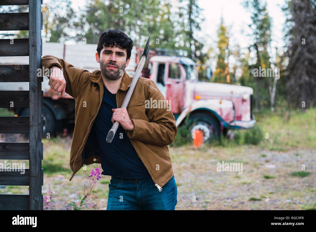 Young man holding axe, standing in front of a broken truck Stock Photo ...