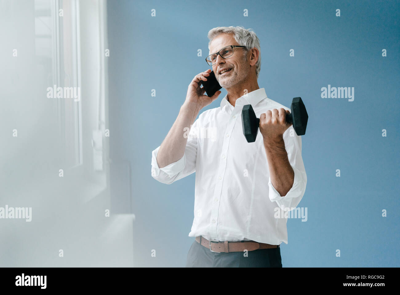 Successful manager using smartphone and training with a dumbbell Stock ...