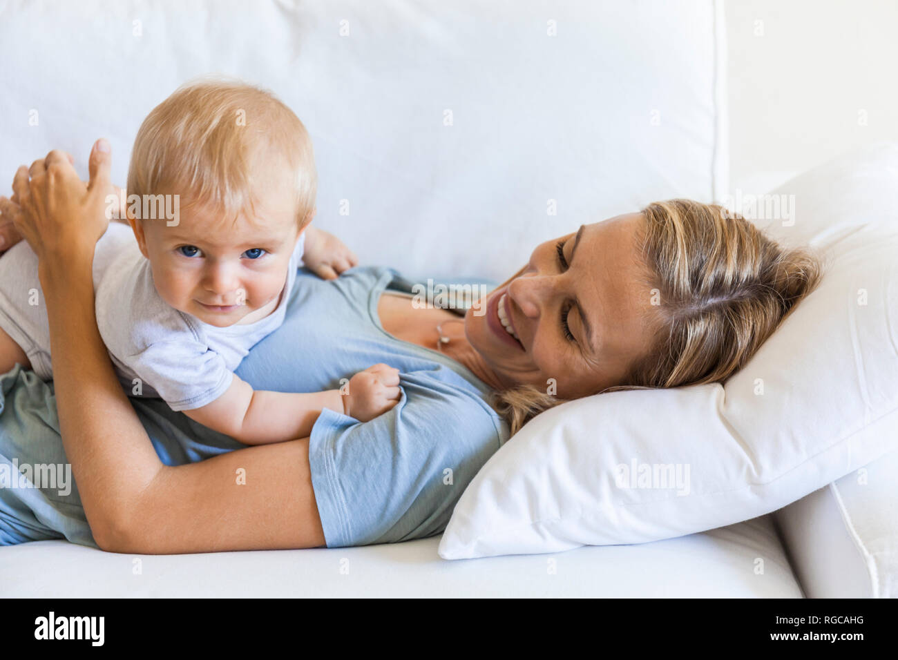 Happy mother cuddling with her baby girl on couch Stock Photo - Alamy