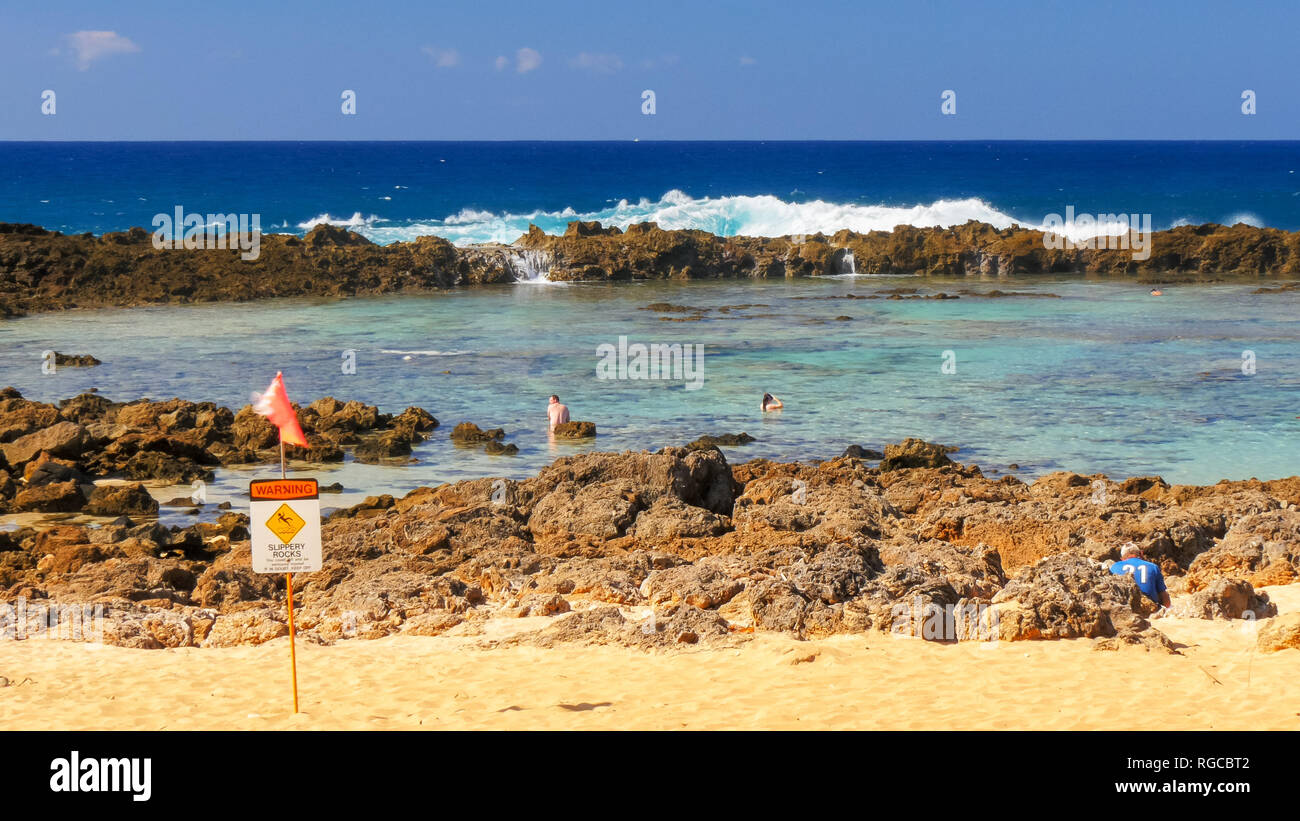 a wave breaks onto the rocks and pours into the tide pool at shark cove ...