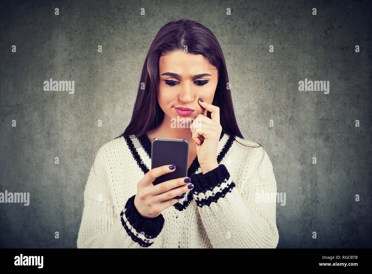 Modern young woman feeling perplexed browsing smartphone in ...