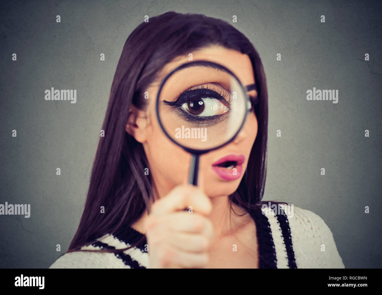 Curious young woman looking through a magnifying glass Stock Photo - Alamy