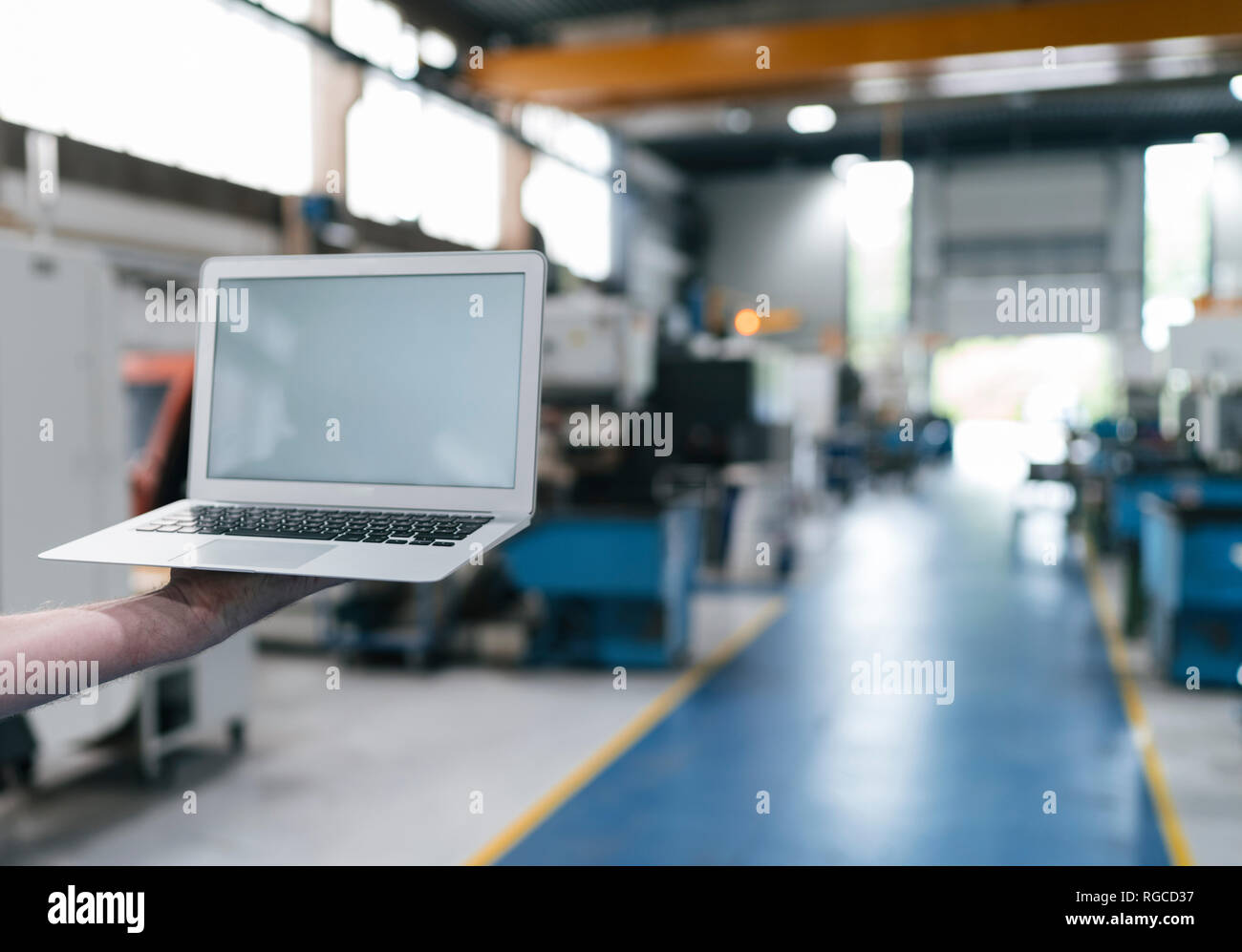 Hand holding laptop blank screen factory workshop hi-res stock ...