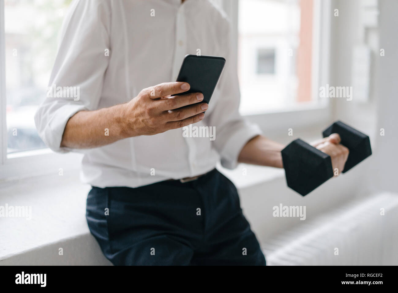 Successful manager using smartphone and training with a dumbbell Stock ...