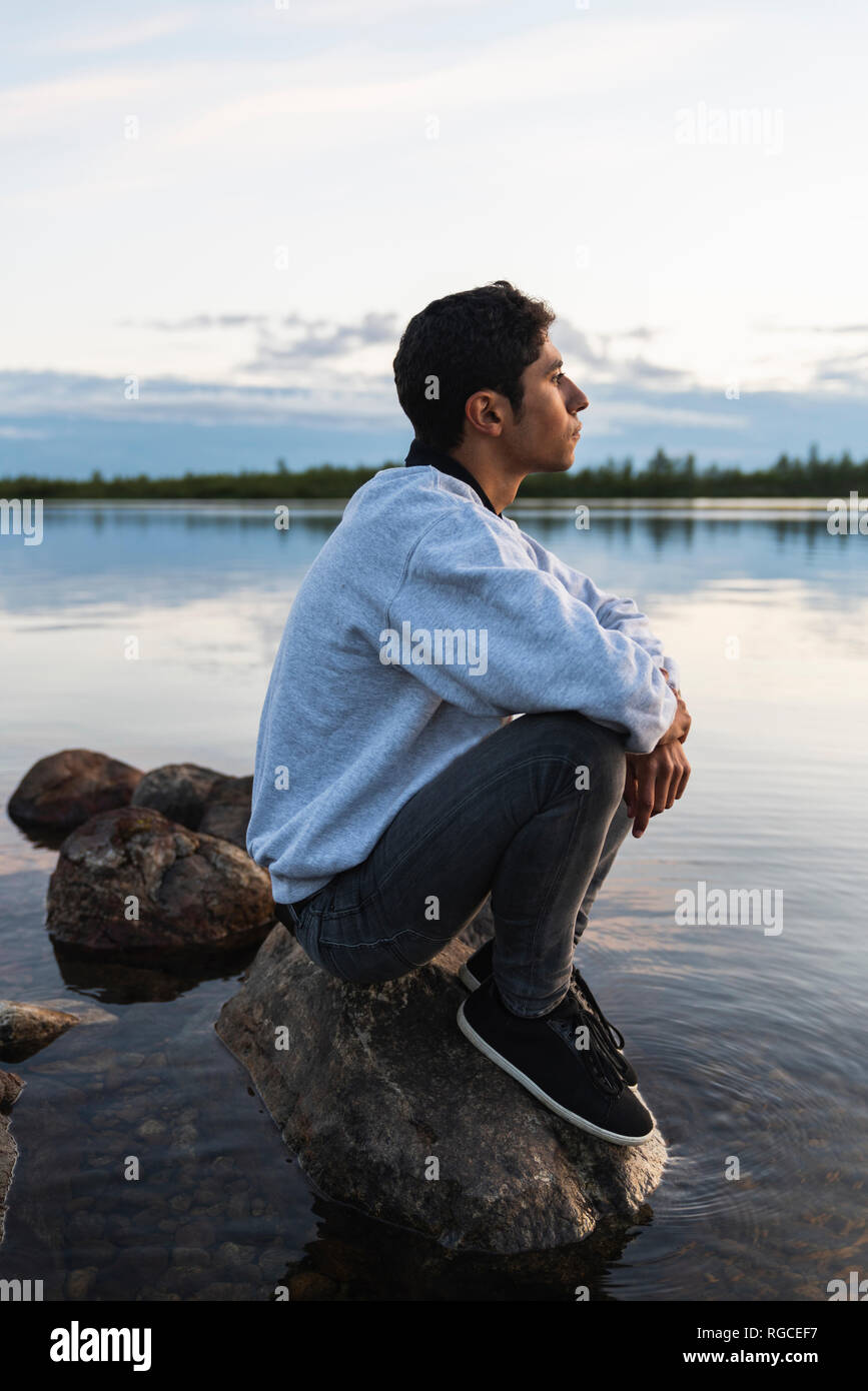 Finland, Lapland, man sitting on a rock in a lake Stock Photo - Alamy