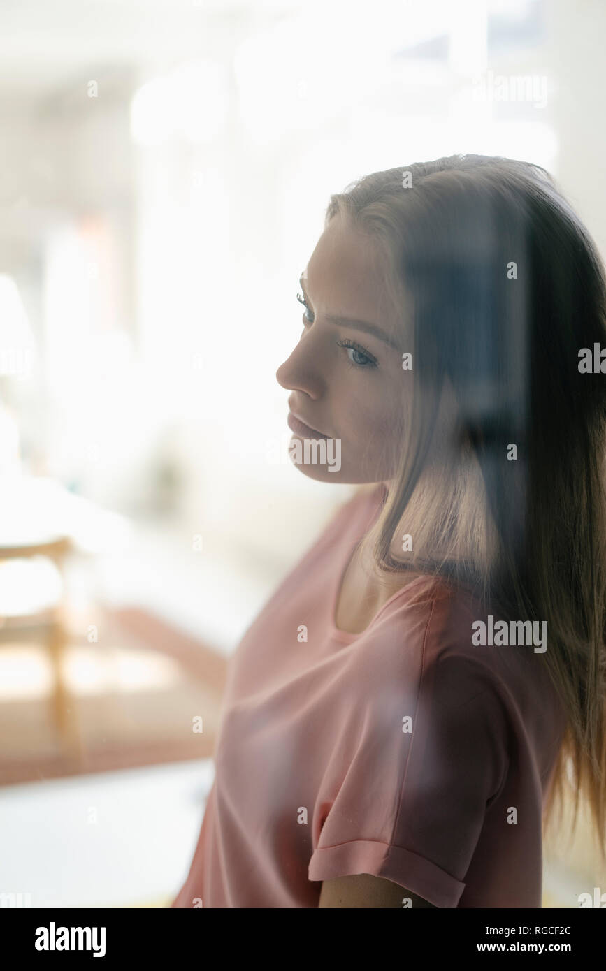 Portrait of pensive young woman behind glass pane Stock Photo - Alamy