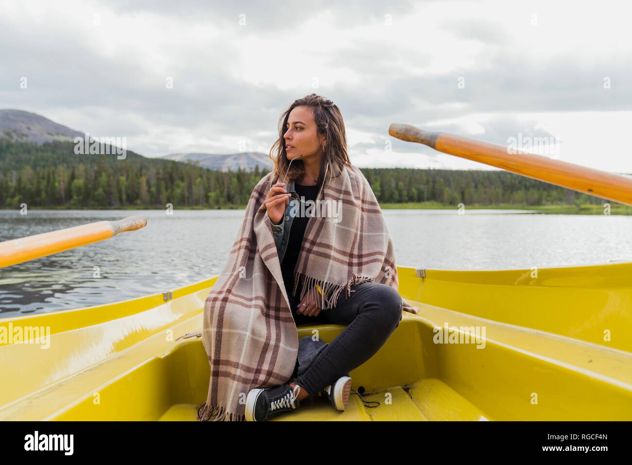 Finland, Lapland, woman wearing a blanket on a boat on a lake Stock ...