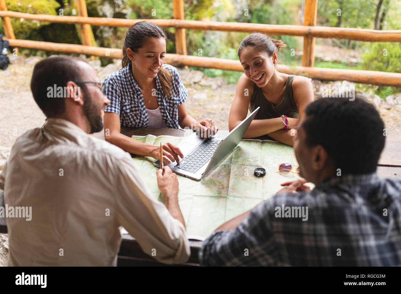 Group of hikers sitting together planning a hiking route using map and ...