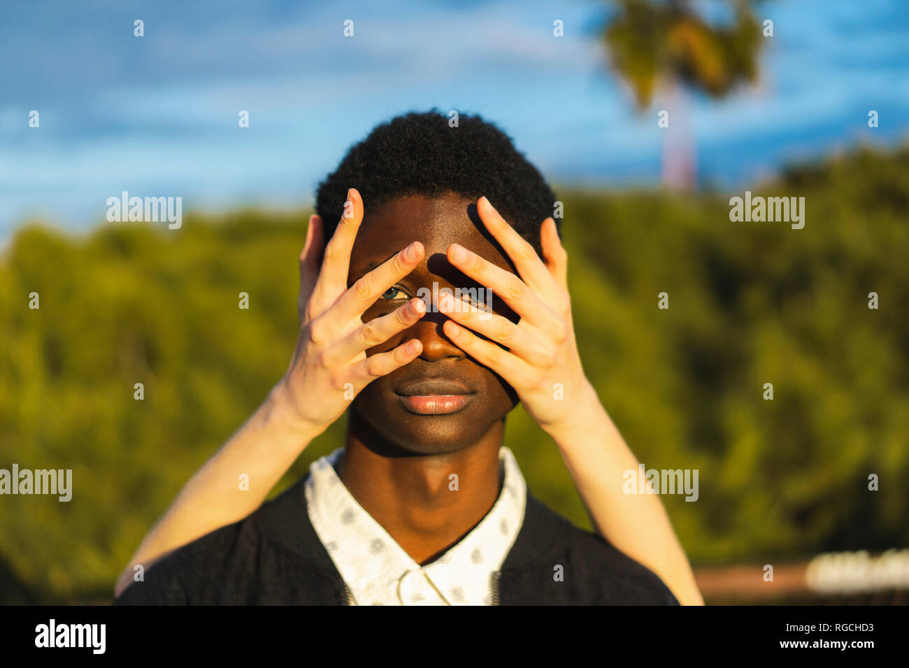 Hands covering eyes of a young black man Stock Photo - Alamy