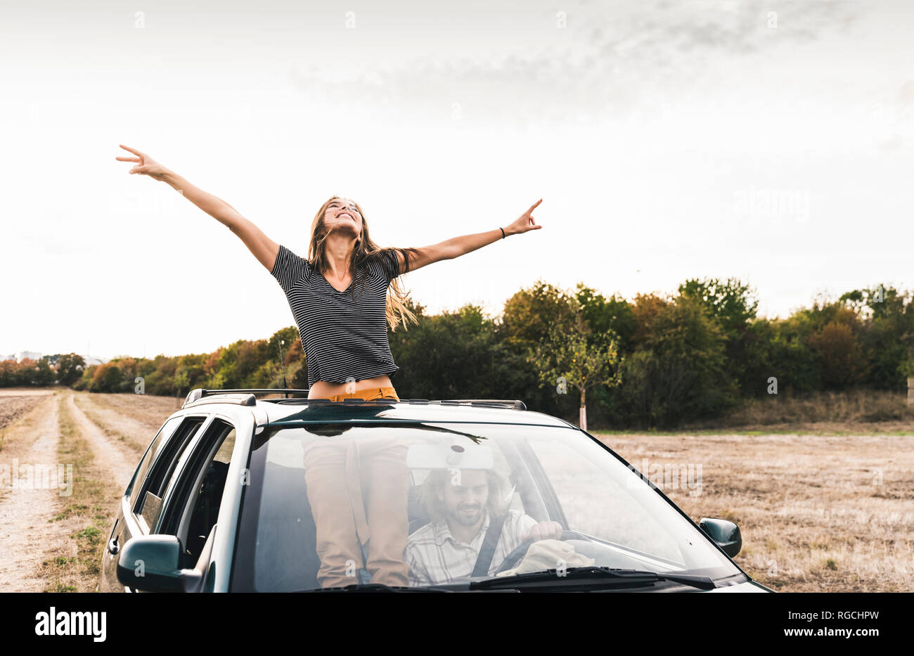 Carefree young woman looking out of sunroof of a car Stock Photo - Alamy