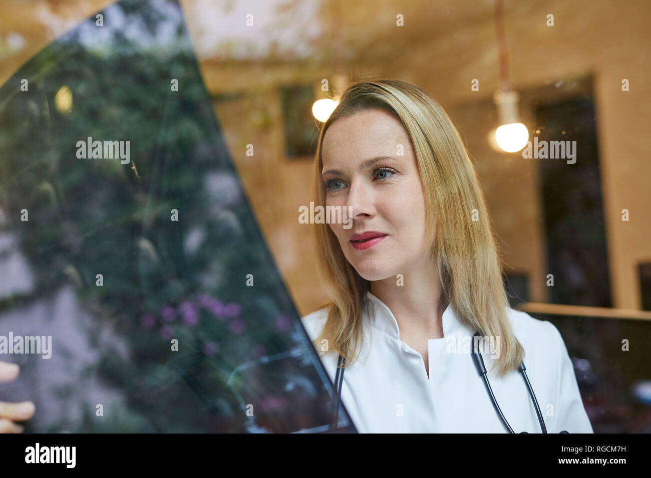 Female doctor looking at x-ray image behind windowpane Stock Photo - Alamy