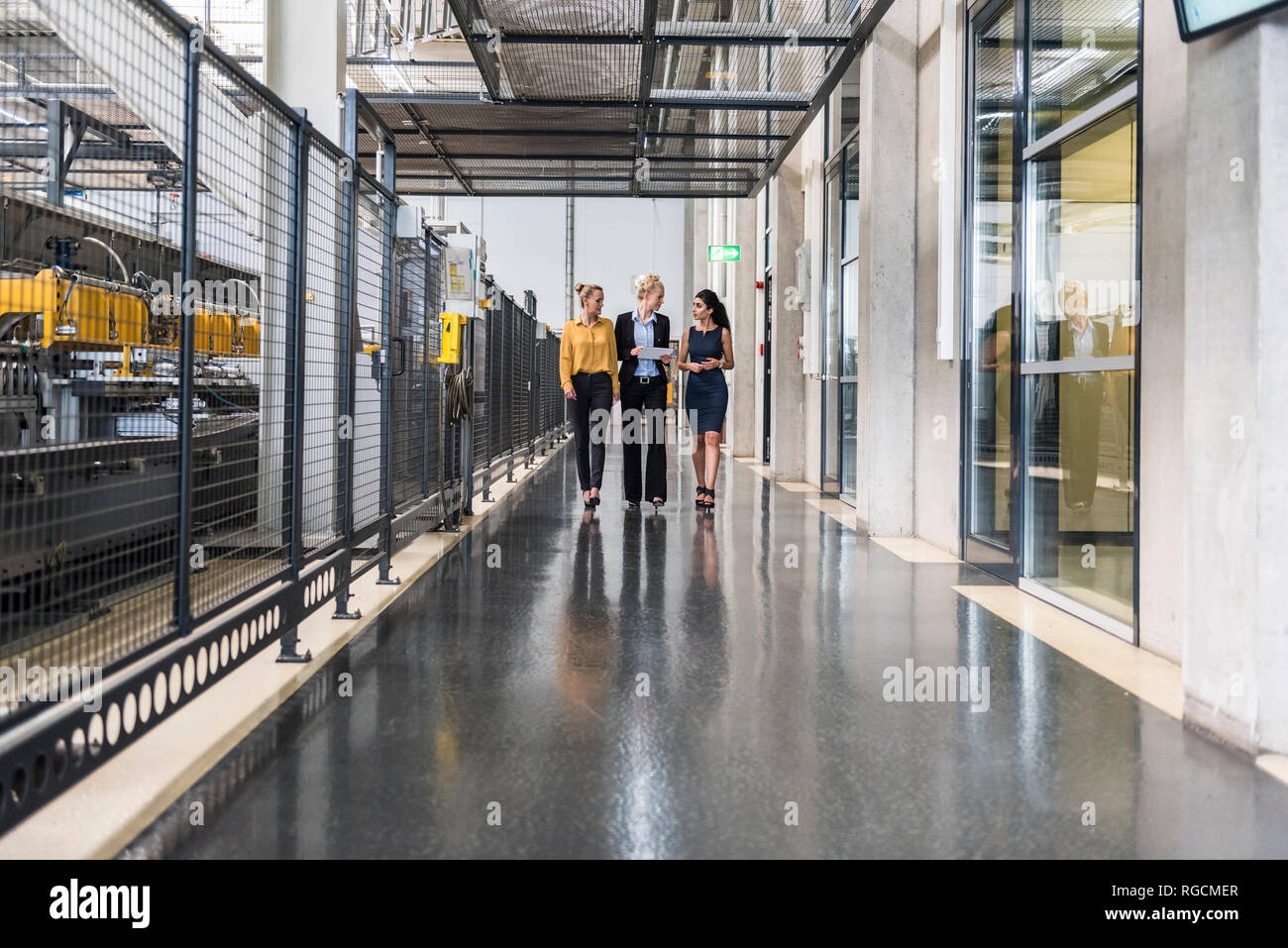 Three women with tablet walking and talking in factory shop floor Stock ...